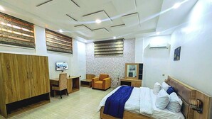 Um quarto com cama, escrivaninha, cadeira e guarda-roupa.