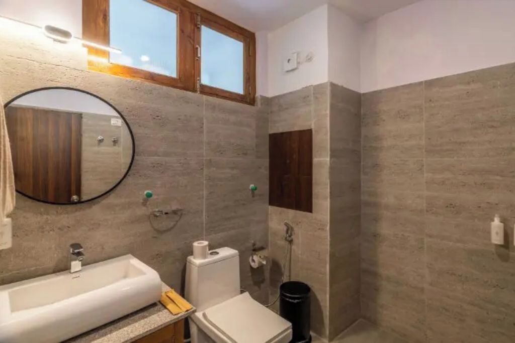 Casa de banho com lavatório, sanita e chuveiro.