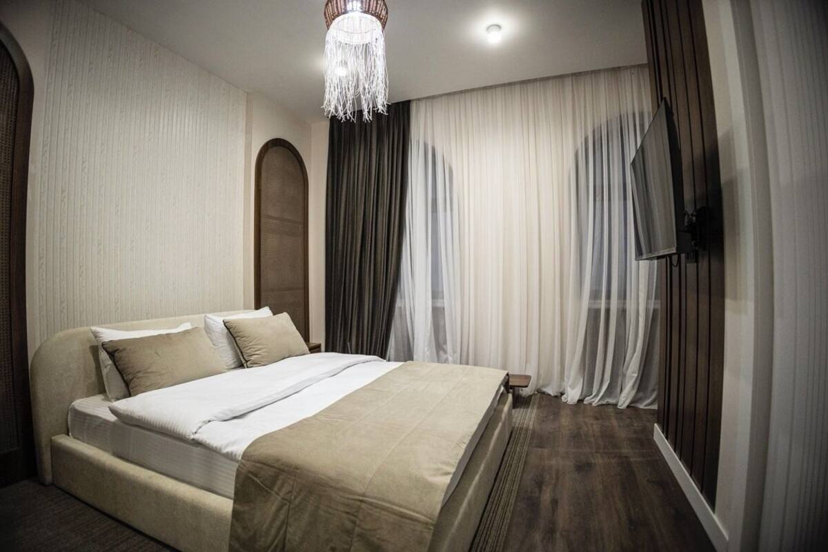 Quarto de hotel moderno com uma cama grande, televisão e um lustre.