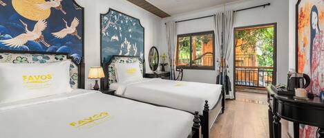 Quarto de hotel com duas camas, uma janela grande e obras de arte nas paredes.