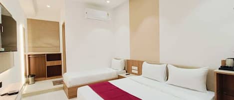 Quarto de hotel com duas camas, um guarda-roupa de madeira, uma TV e um aparelho de ar condicionado.