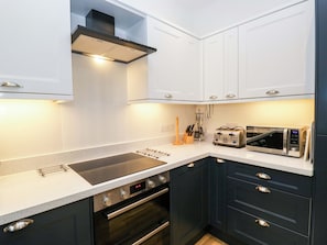 Uma cozinha moderna com armários brancos, fogão preto e forno embutido.