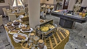 Disposição de buffet com diversos alimentos e um canto de café em uma área de refeições de hotel.