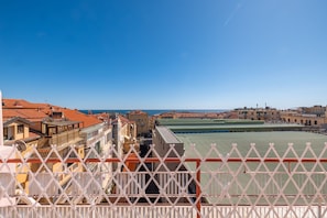 Vista de uma área costeira com edifícios, um campo esportivo e céu claro.