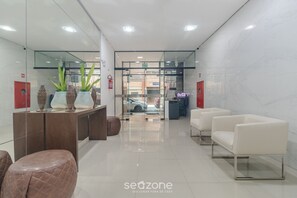 Uma área de recepção moderna com parede de vidro, balcão de atendimento e assentos.