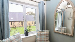 Quarto com um banco junto à janela, um espelho e vista para um edifício.