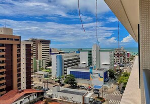 Paisagem urbana com edifícios altos, céu claro e vista para o oceano.