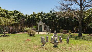 Um jardim com uma estrutura de pedra, estátuas e diversas árvores.