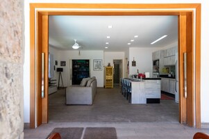 Uma sala de estar ampla com sofá, mesa de jantar com cadeiras, cozinha com armários e ventilador de teto.
