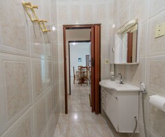 Um banheiro com pia, espelho e porta-toalhas.