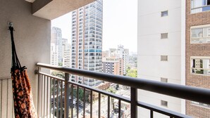 Varanda com vista para edifícios altos e uma bolsa pendurada.