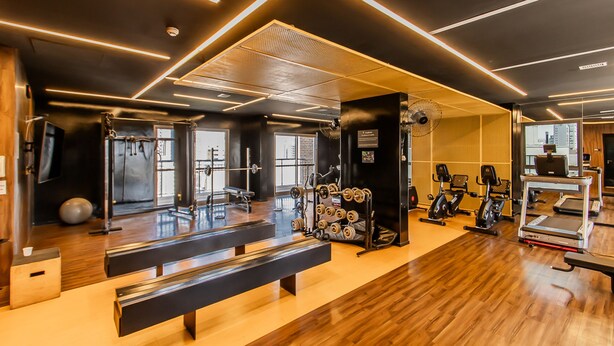 Uma academia moderna com piso de madeira, equipamentos de ginástica e um espelho grande.