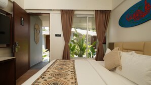 Quarto de hotel com cama, televisão, porta e vista para o exterior.