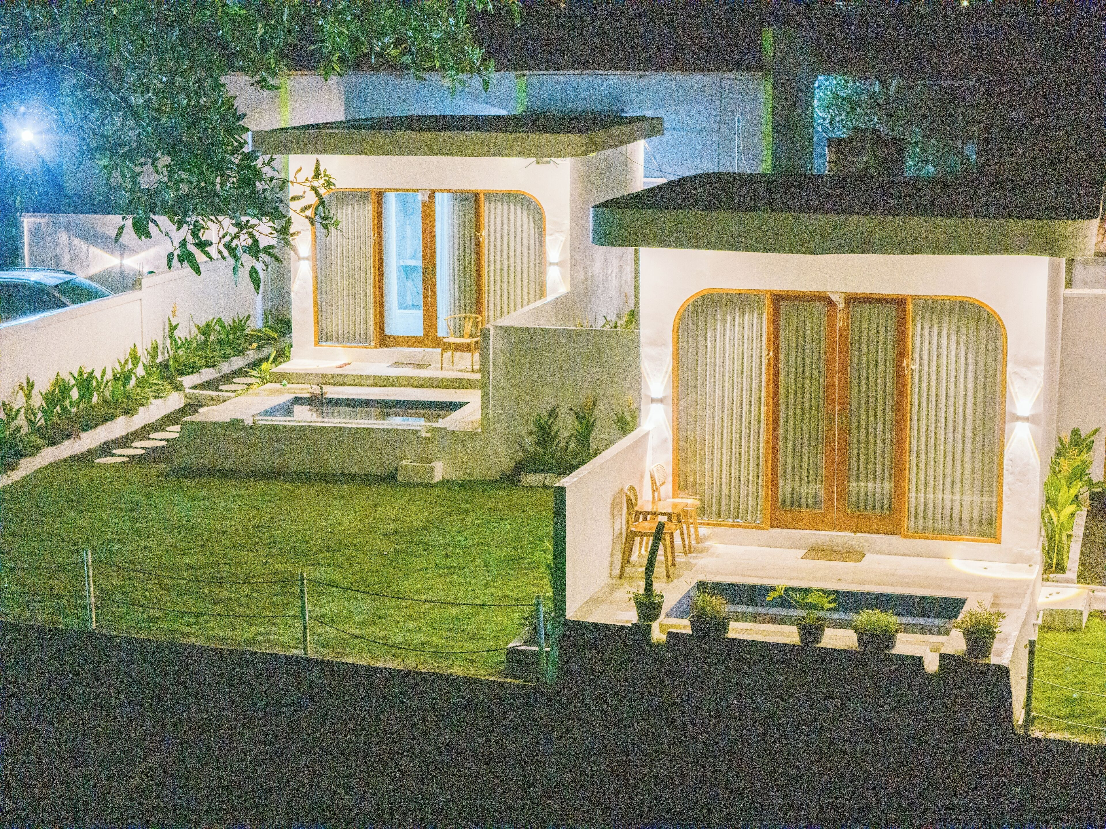 Uma casa moderna com um gramado bem cuidado, uma piscina pequena e uma área de pátio com assentos.