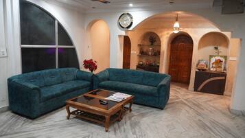 Sala de estar com dois sofás verde-água, uma mesa de centro de madeira e uma janela grande.