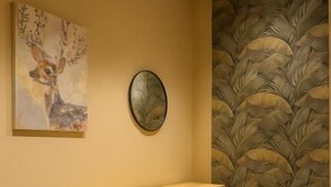 Um corredor com um aparador de madeira, um espelho fixado na parede e um quadro de um veado.