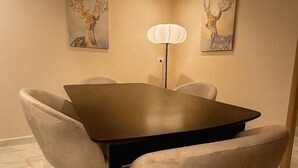 Uma área de jantar com uma mesa redonda, quatro cadeiras e duas luminárias fixadas na parede.