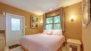 Quarto com cama, mesa de cabeceira, porta, janela com cortinas e luminária na parede.