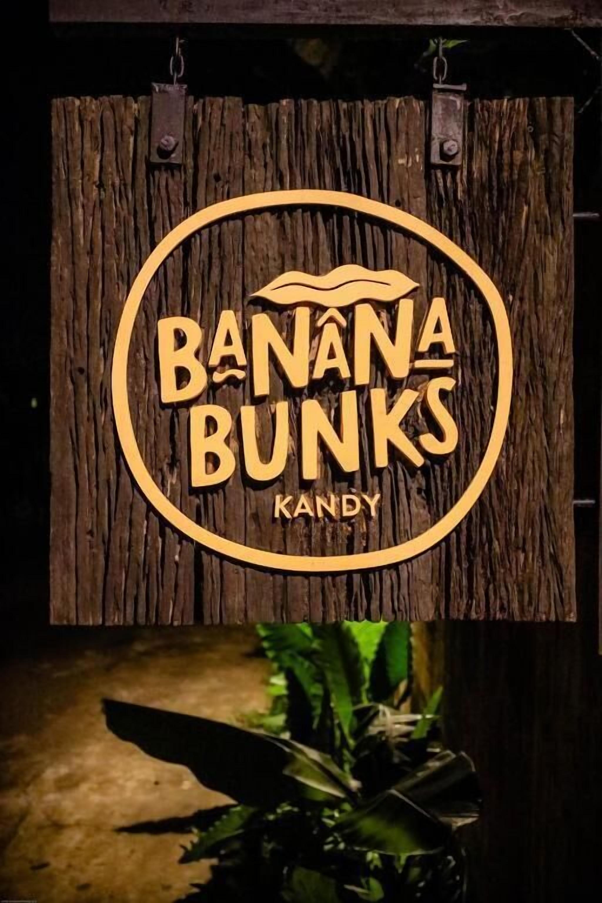 Uma placa de madeira com o texto 'BANANA BUNKS KANDY'.