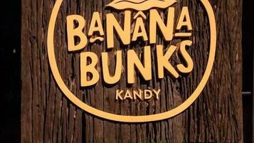 Uma placa de madeira com o texto 'BANANA BUNKS KANDY'.