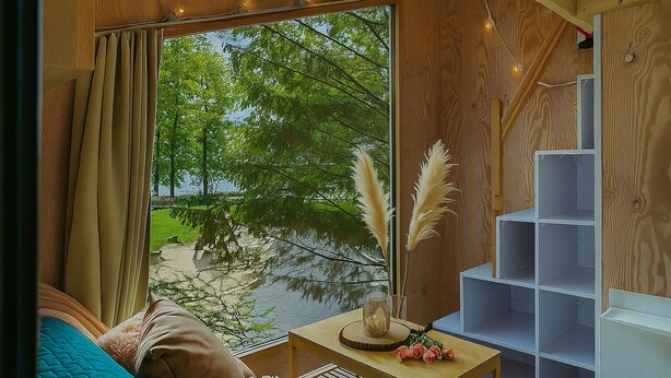 Um quarto acolhedor com vista para um lago, uma escada de madeira e uma pequena mesa com flores.