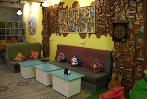 Uma sala de estar acolhedora com um sofá verde, duas mesas de centro brancas e almofadas coloridas.