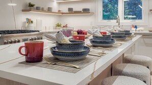 Uma cozinha moderna com ilha central, bancadas brancas e tigelas de cerâmica azuis.