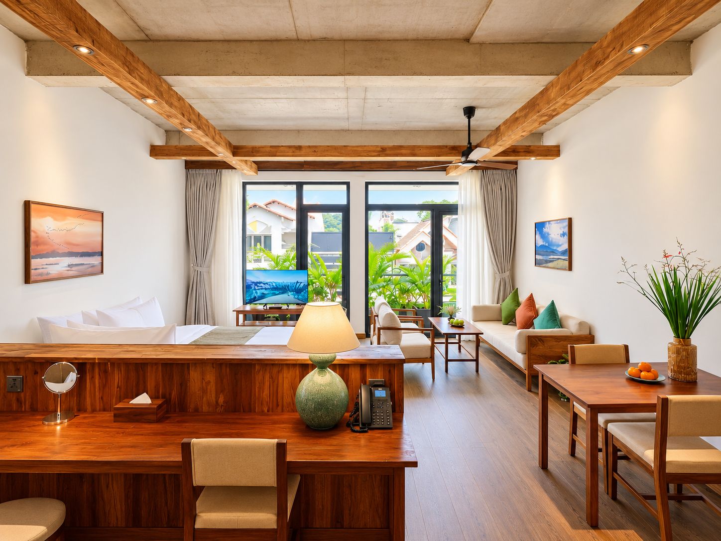 Quarto de hotel com escrivaninha de madeira, sofá, mesa de jantar e vista para o exterior.