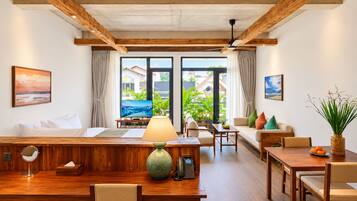 Quarto de hotel com escrivaninha de madeira, sofá, mesa de jantar e vista para o exterior.