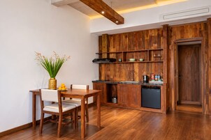 Cozinha moderna com armários de madeira, uma mesa de jantar com cadeiras e uma pequena geladeira.