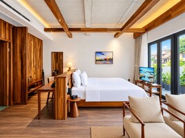 Quarto de hotel com cama, escrivaninha, cadeira, televisão e um quadro.