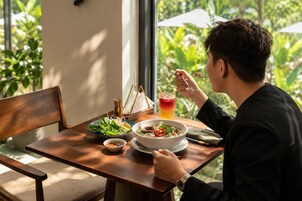 Alguém jantando à mesa, com uma tigela de comida, uma bebida e um prato de legumes.