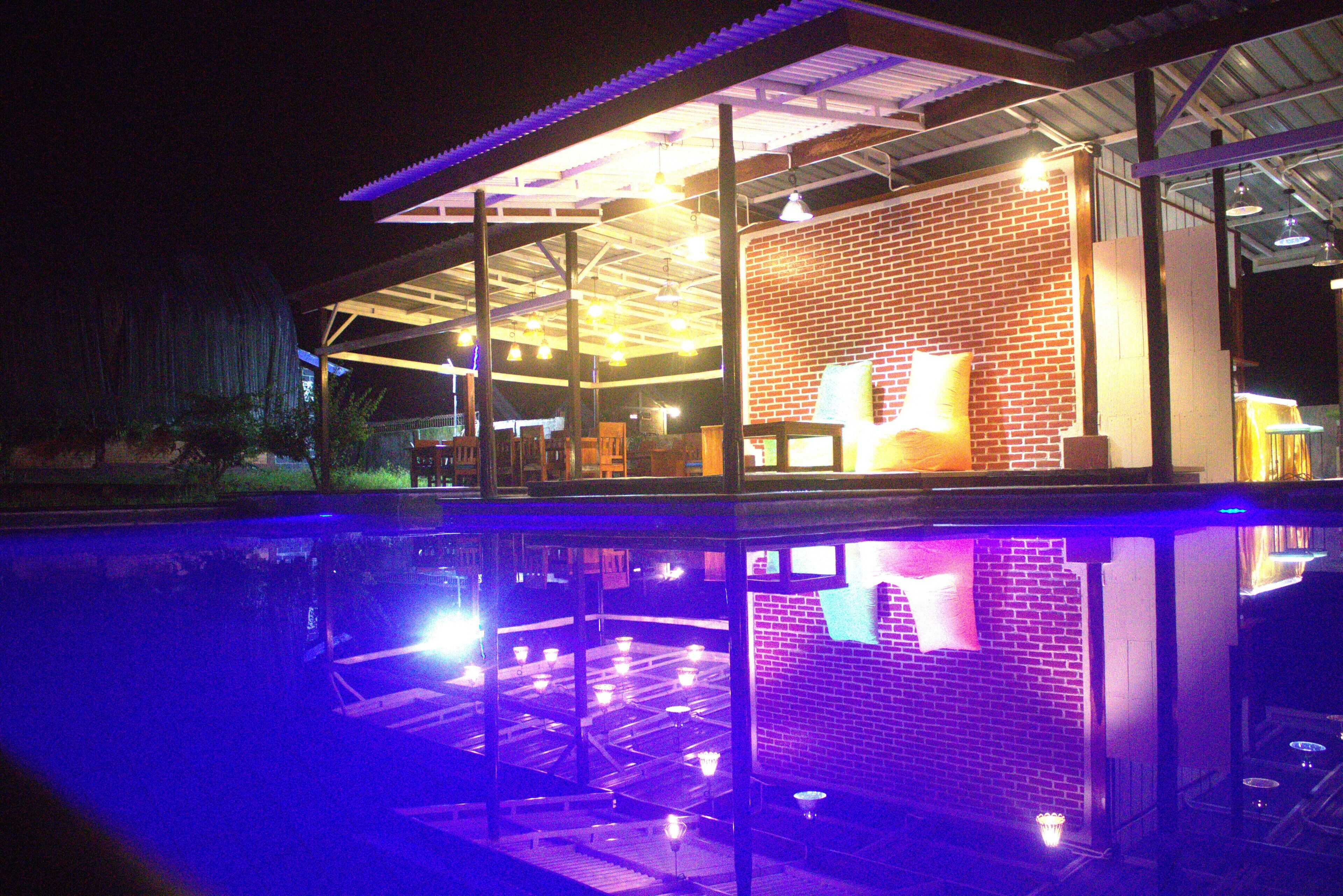 Um edifício moderno com fachada de vidro, parede de tijolos e área de piscina.