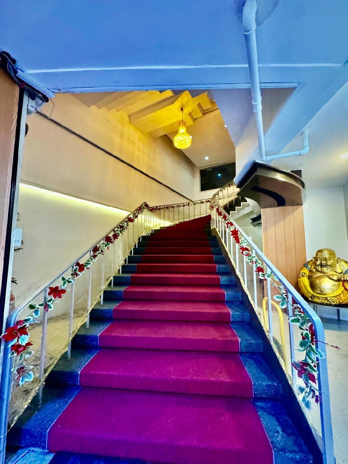 Uma escadaria com tapete vermelho e guarda-corpos brancos, decorada com flores vermelhas.