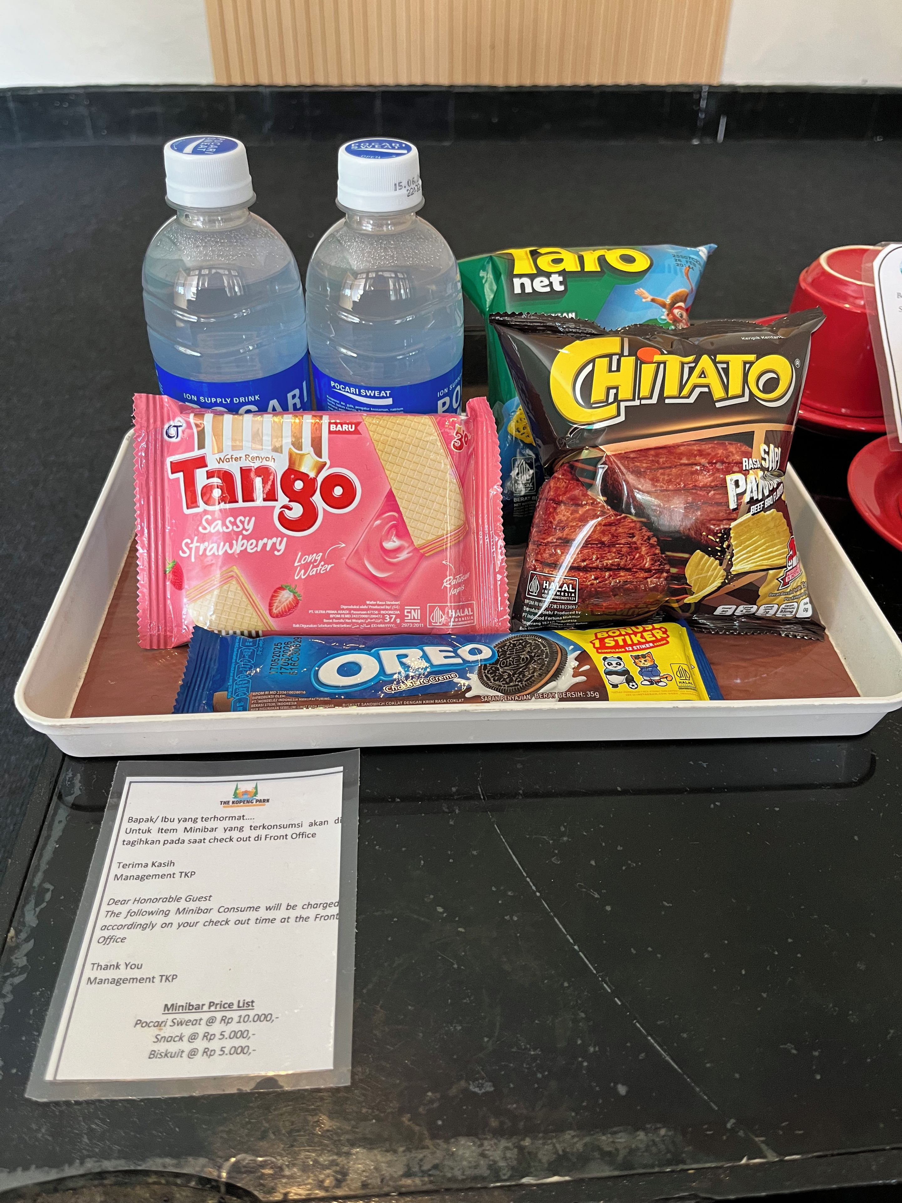 Uma bandeja com diversos petiscos e bebidas, incluindo Tango, Oreos e um pacote de batatas.