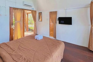 Quarto de hotel com uma cama grande, televisão de tela plana e porta para área externa.