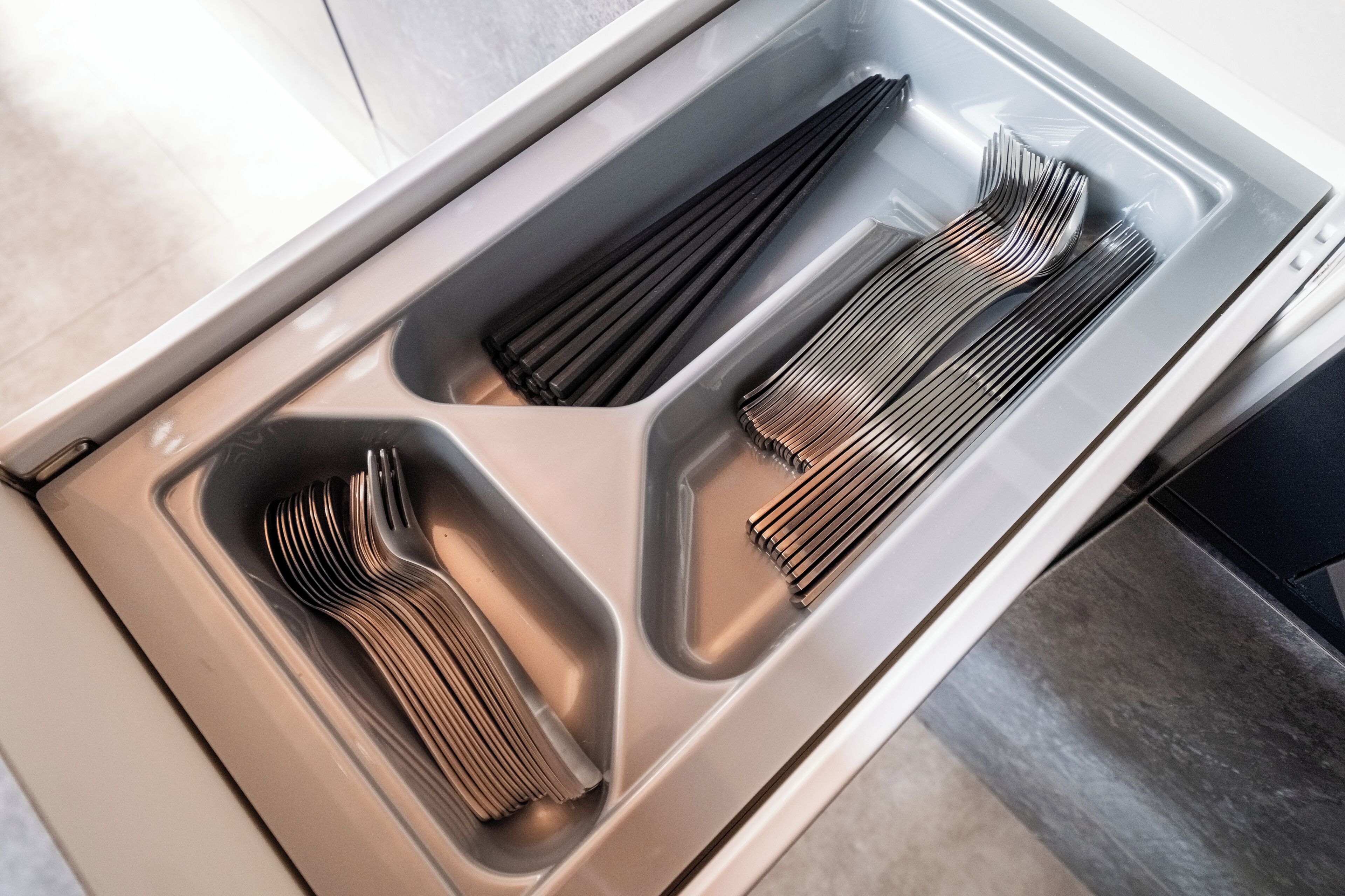 Uma gaveta de cozinha com vários porta-utensílios.