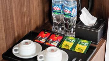 Minibar de hotel com água engarrafada, cafeteira e sachês de chá.