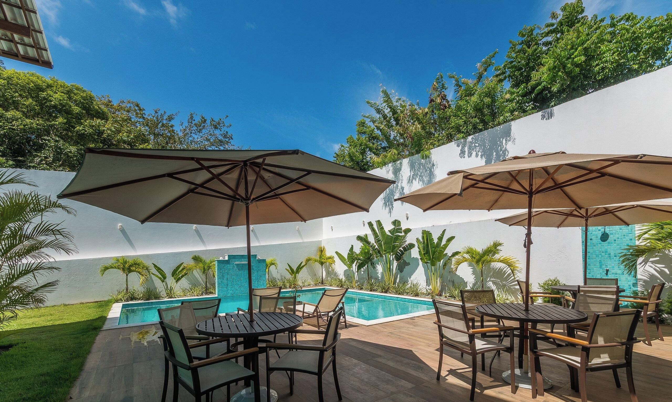 Uma área de piscina externa com espreguiçadeiras e guarda-sóis.