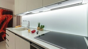 Uma cozinha moderna com bancada preta elegante, torneira de aço inoxidável e duas plantas em vasos.
