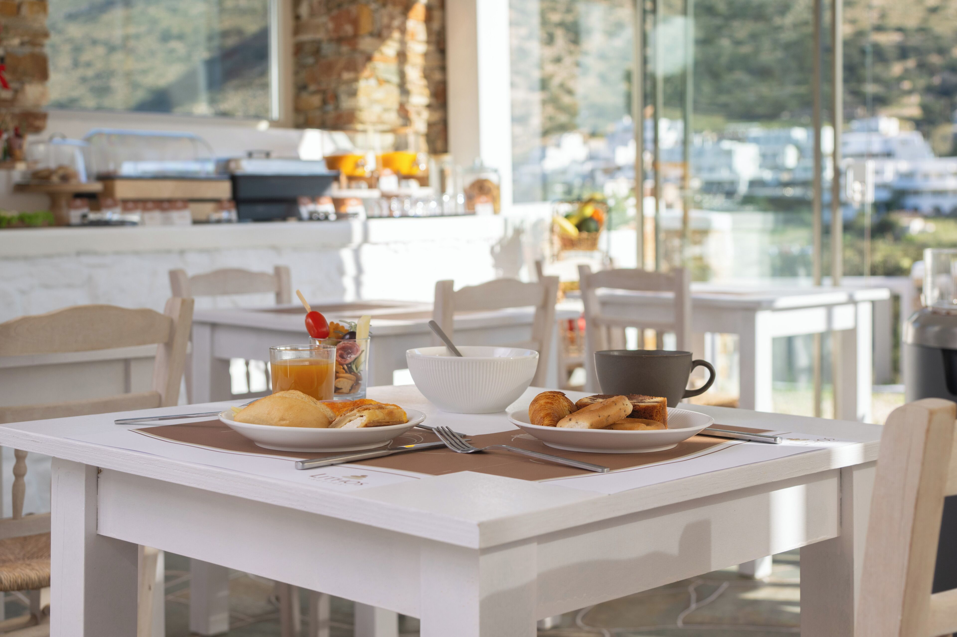 Uma mesa de café da manhã com pratos de comida, um copo de suco de laranja e uma xícara de café.