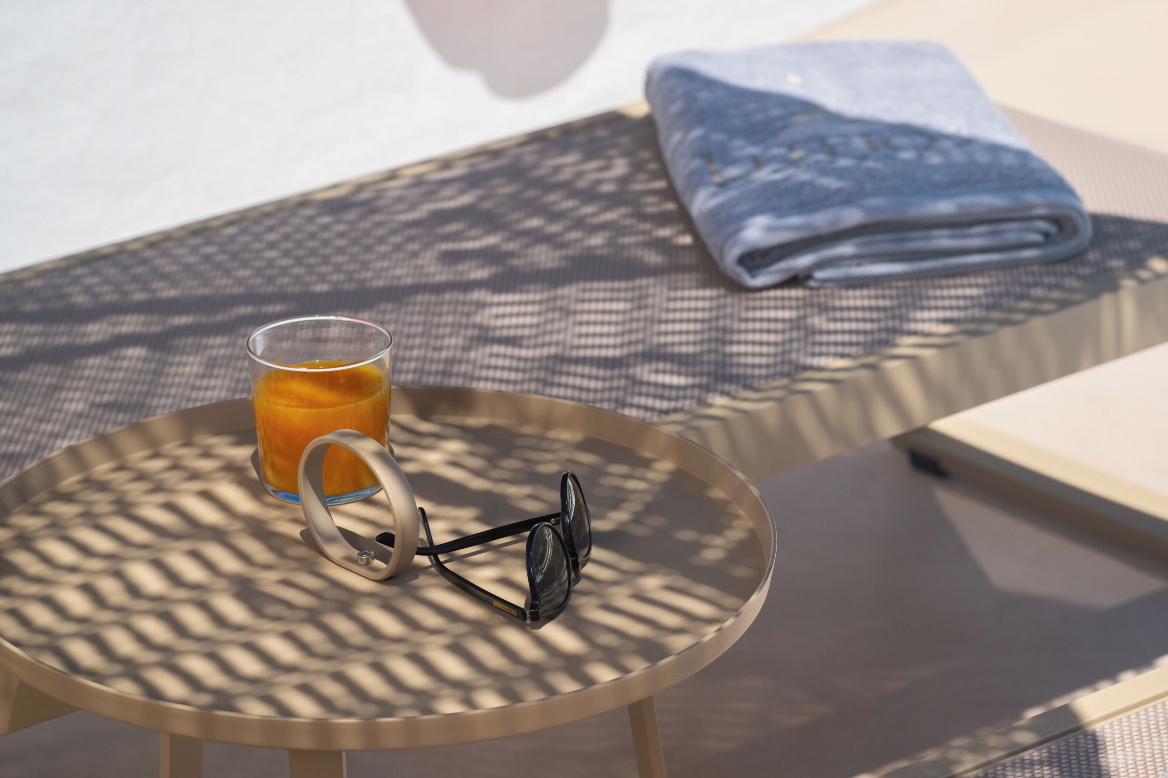 Uma mesa redonda com um copo de sumo de laranja e um par de óculos de sol.