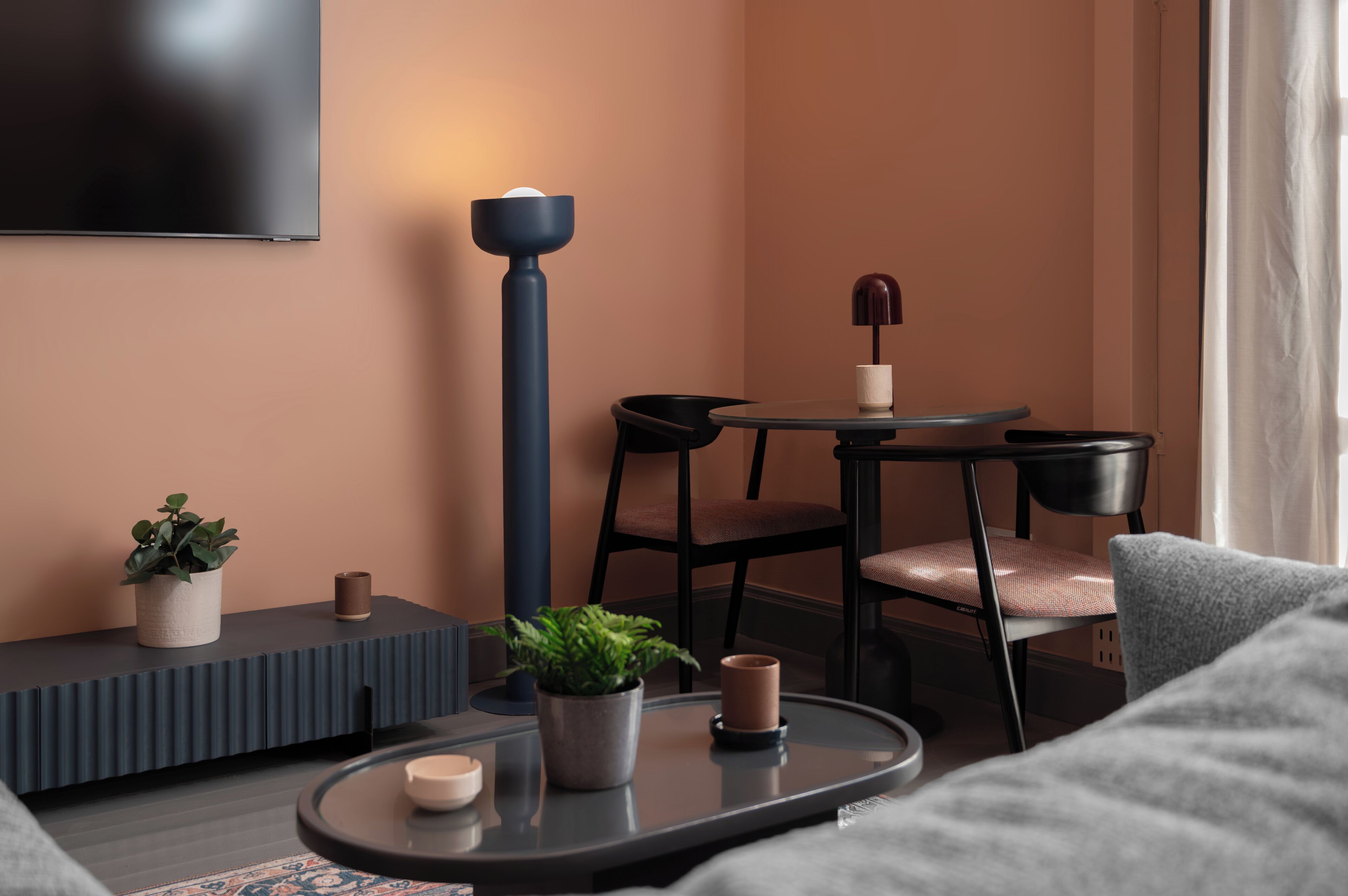 Uma sala de estar moderna com sofá, mesa de centro, TV e um espaço de refeições com cadeiras e mesa.