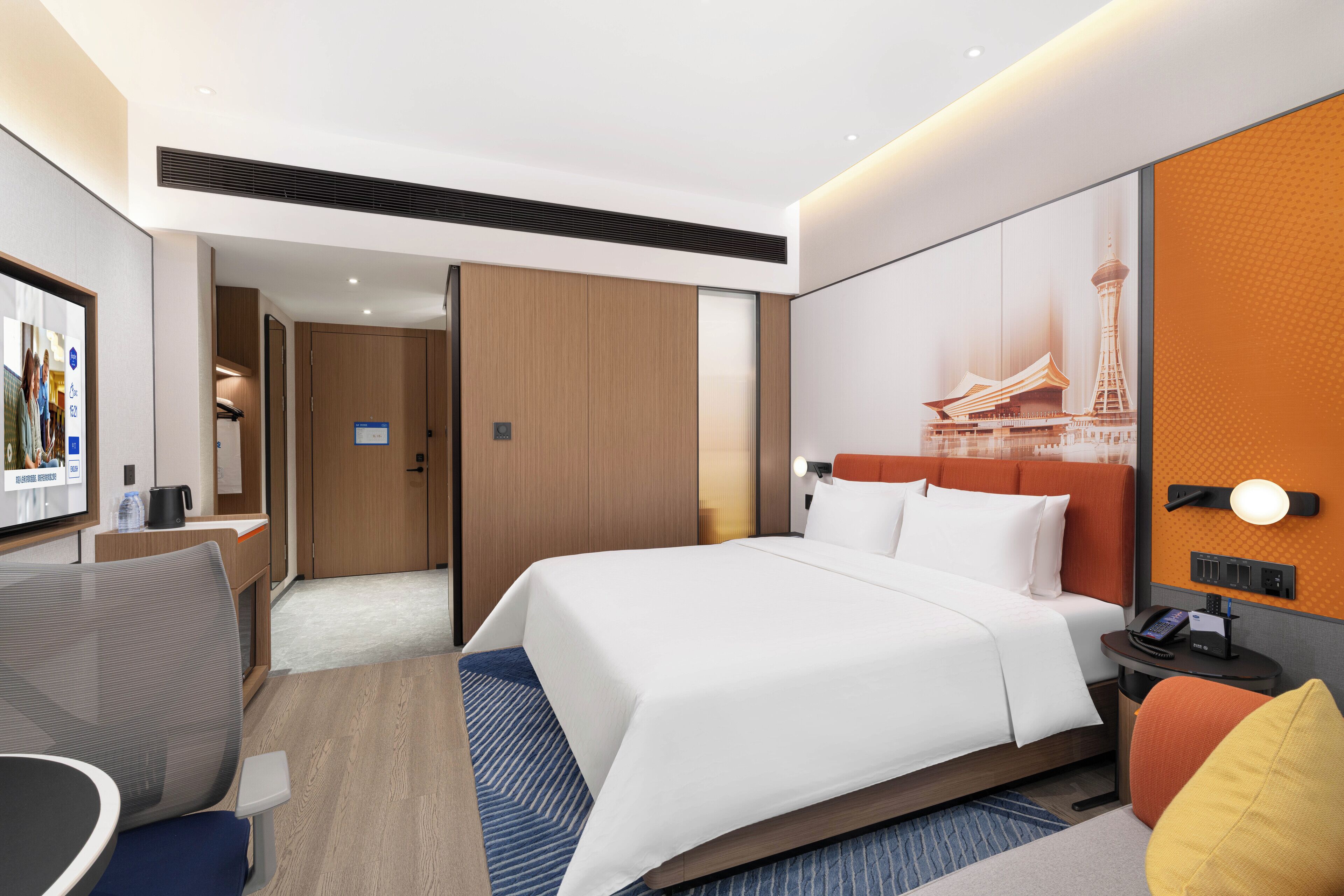 Quarto de hotel moderno com uma cama grande, uma mesa com cadeira, um banheiro e vista para uma torre.