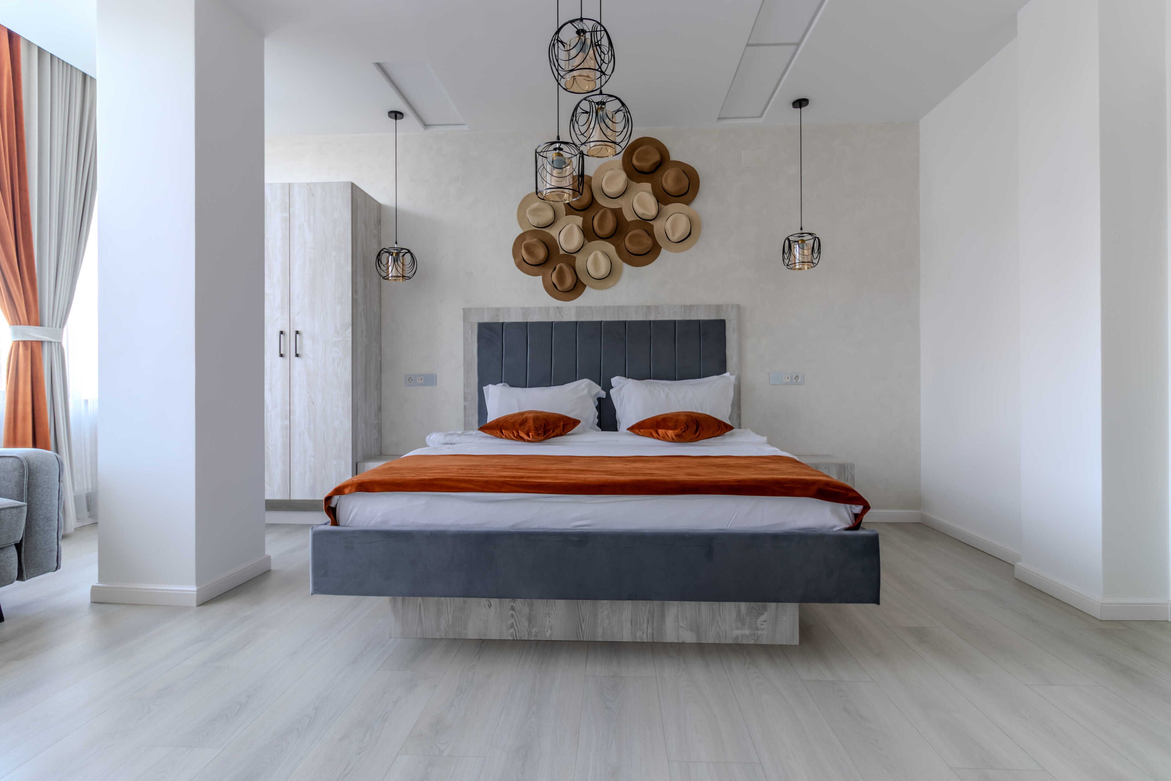 Quarto moderno com cama, guarda-roupa e espaço para chapéus na parede.