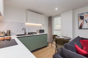 Um espaço compacto com cozinha compacta, área de refeições e sofá com almofadas vermelhas.