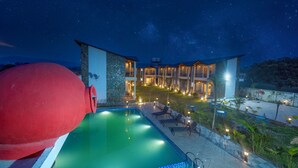 Um hotel com piscina, área de estar ao ar livre e vista para o céu noturno.