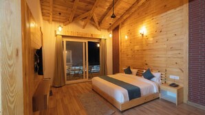 Quarto de madeira com cama, mesa de cabeceira e uma porta de vidro deslizante para uma área externa.