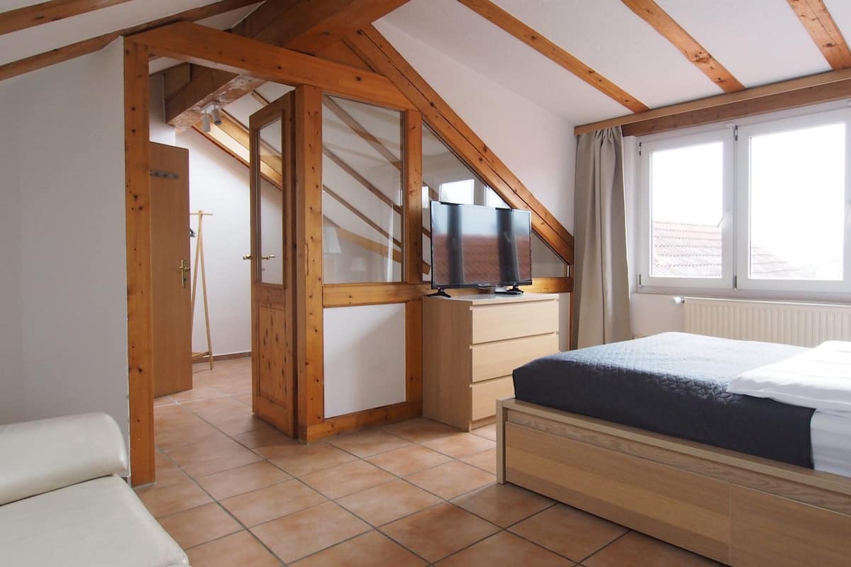 Quarto com cama, cômoda, televisão e janela.