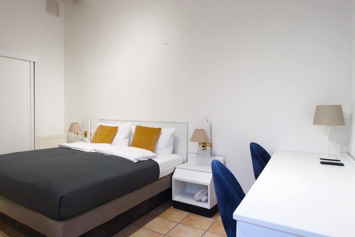 Quarto de hotel com cama, escrivaninha e cadeira.